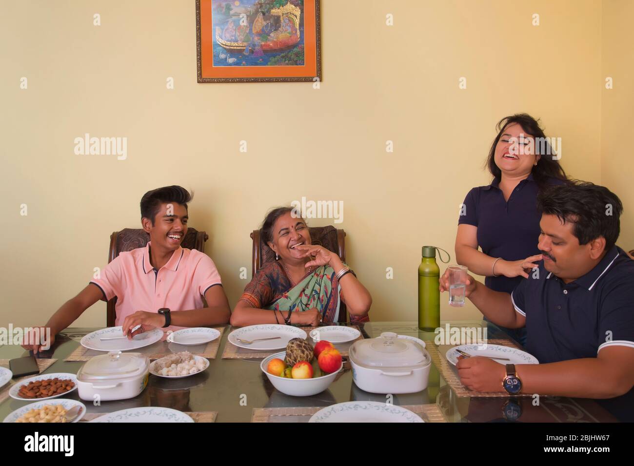 Happy family sitting around the dining table at home Stock Photo - Alamy