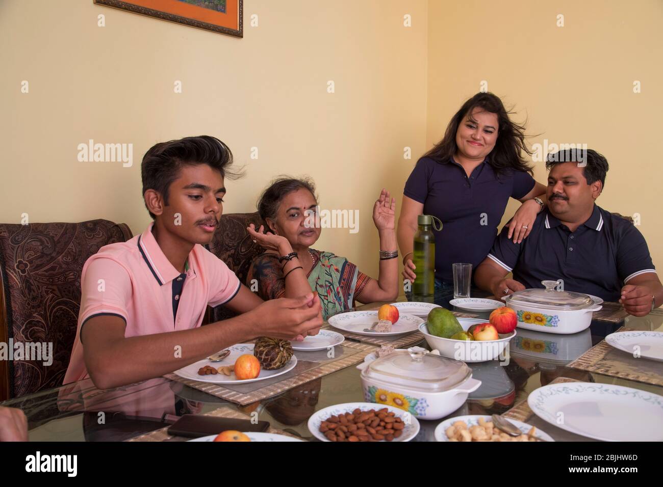 Happy family sitting around the dining table at home Stock Photo - Alamy