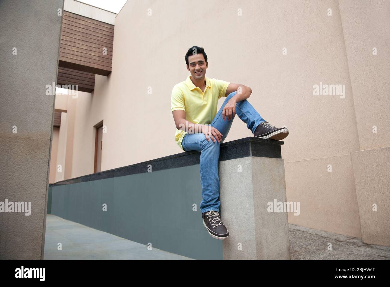 Portrait of a man sitting on a wall Stock Photo - Alamy