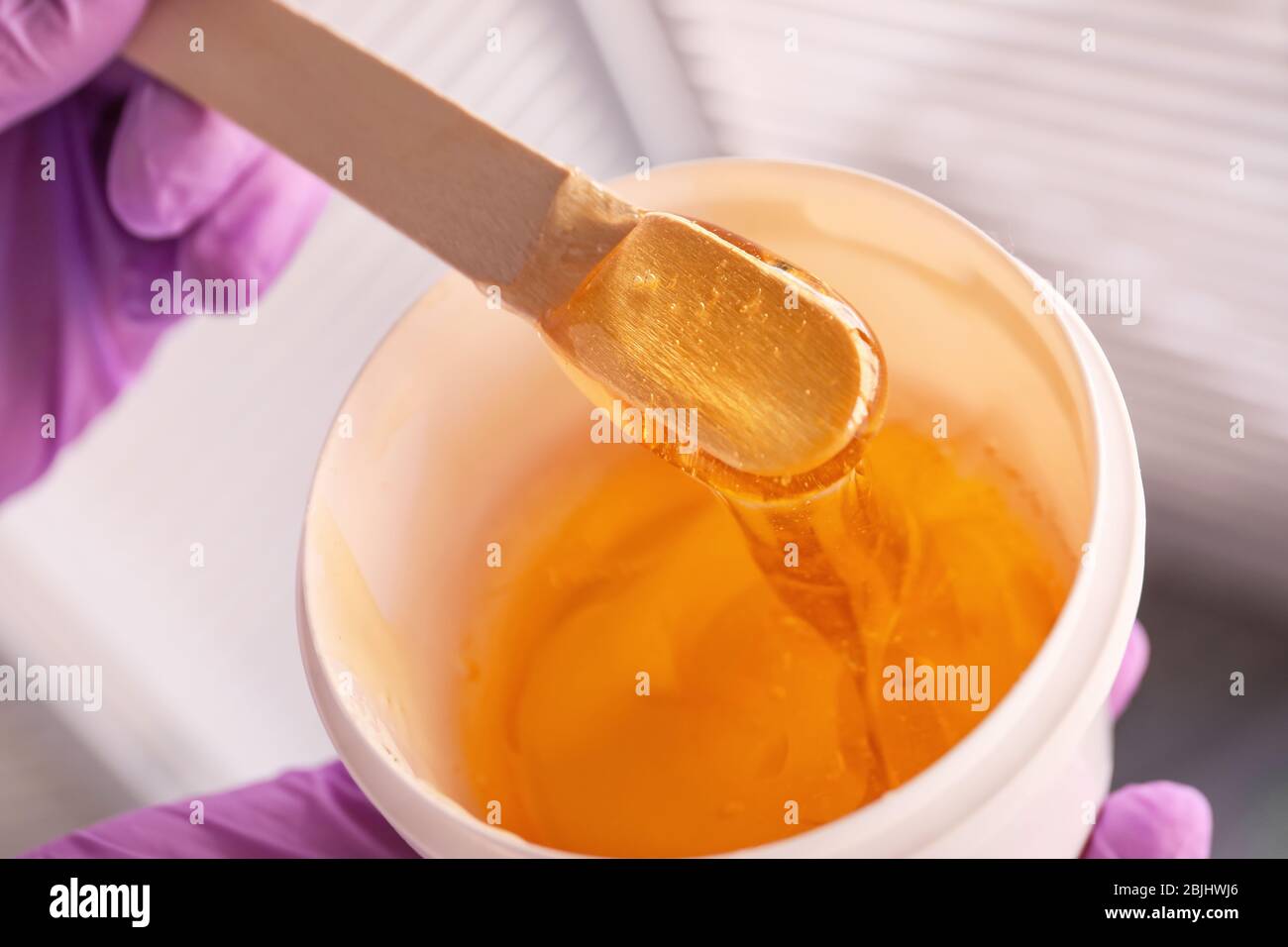 Hands of beautician holding plastic bucket with sugaring paste and ... Hands of beautician holding plastic bucket with sugaring paste and ...