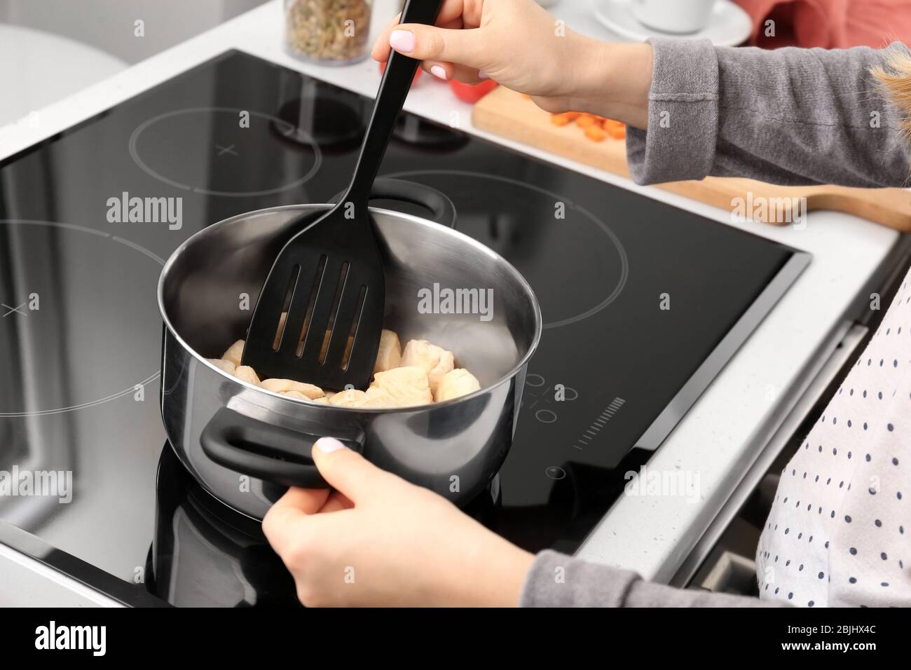 Woman cooking turkey chili on modern stove in kitchen Stock Photo - Alamy