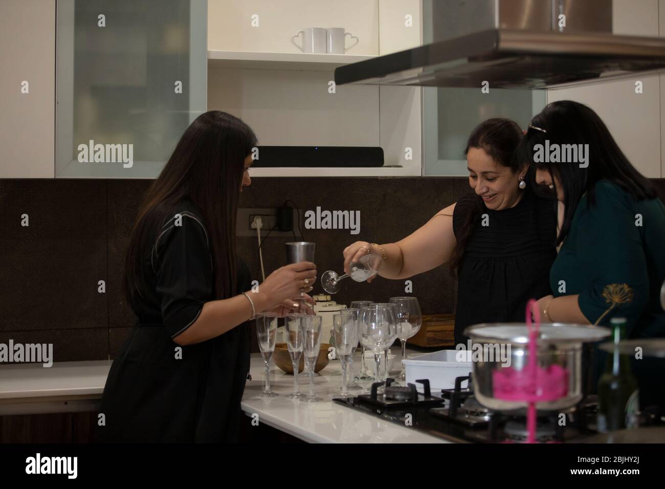 Friends sharing a light moment while pouring drinks at a party Stock ...
