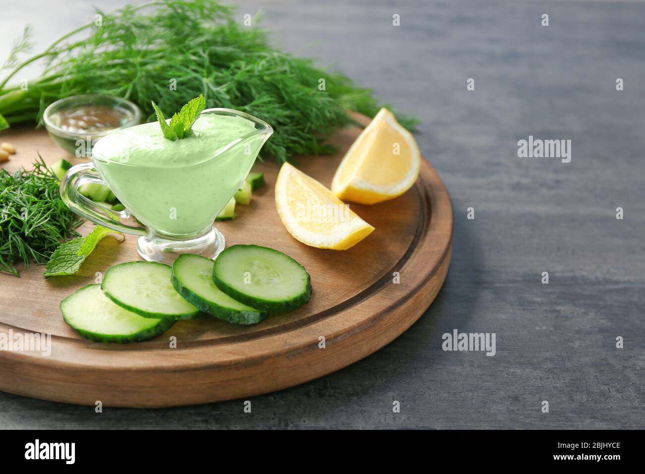 Delicious yogurt sauce in gravy boat with ingredients on grunge ...