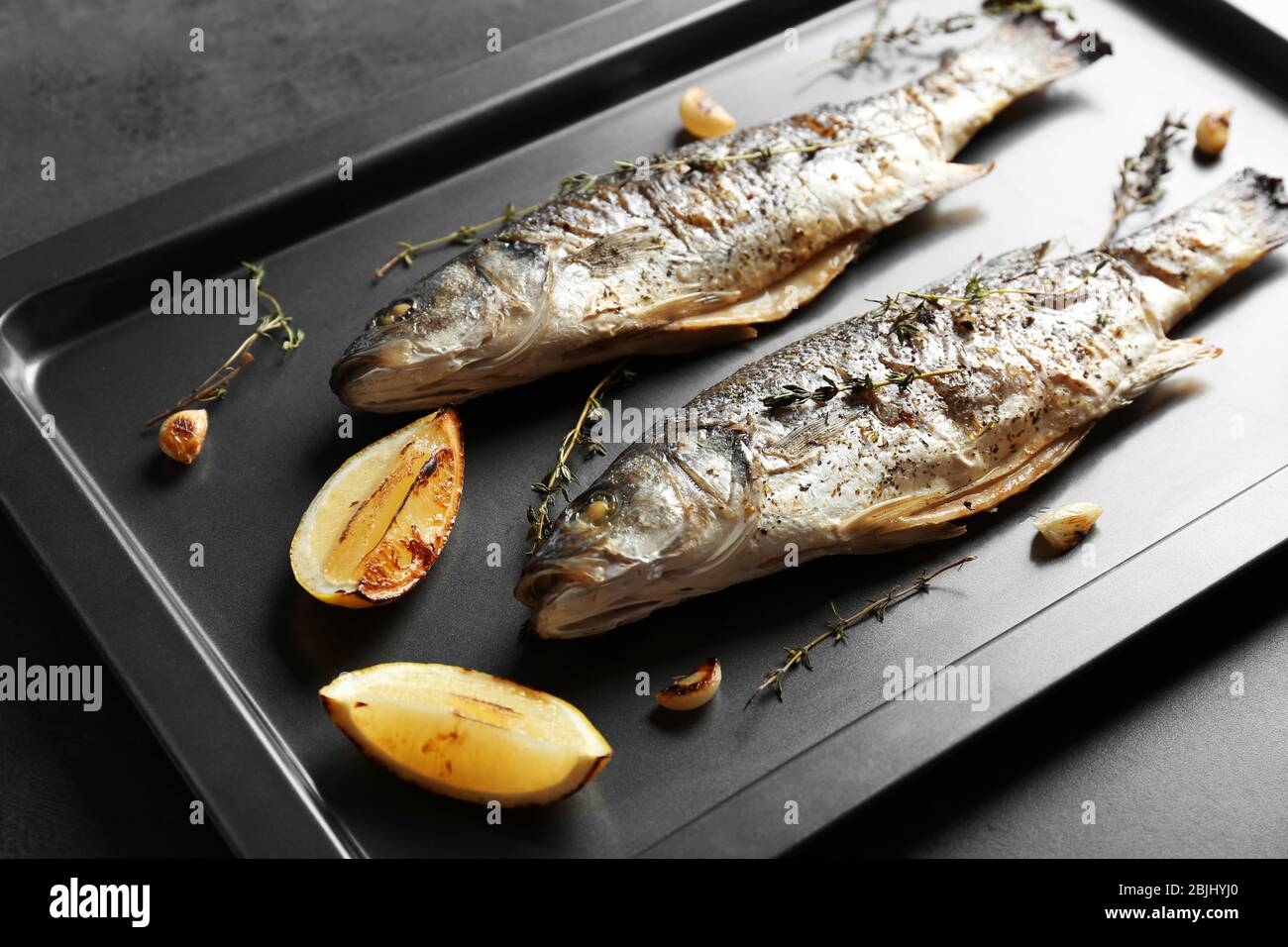 Baking sheet with fried fish on dark background Stock Photo - Alamy
