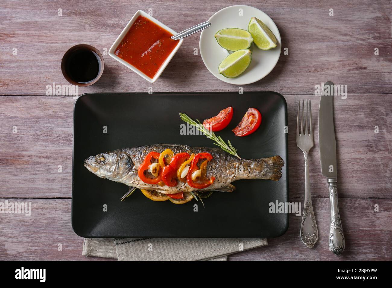 Plate with baked sea bass fish on table Stock Photo - Alamy
