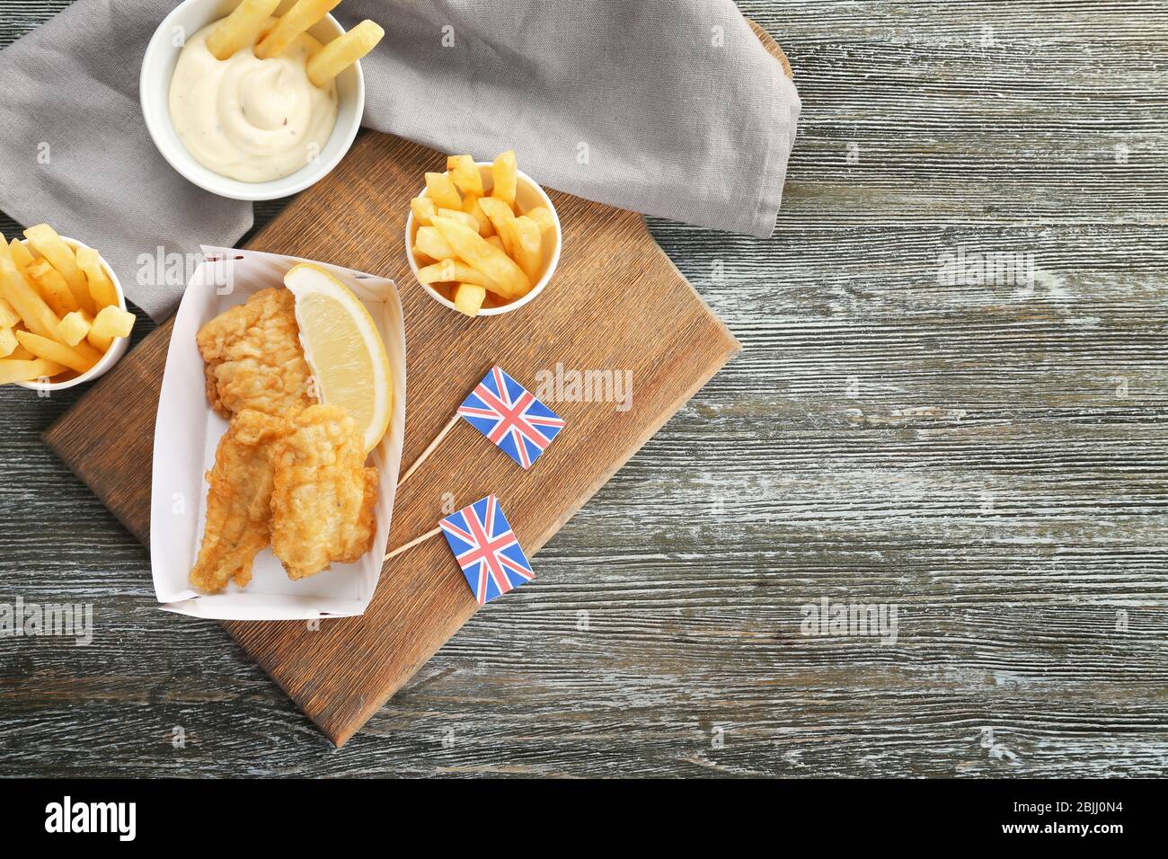 Tasty fried fish and potato chips on wooden table Stock Photo - Alamy