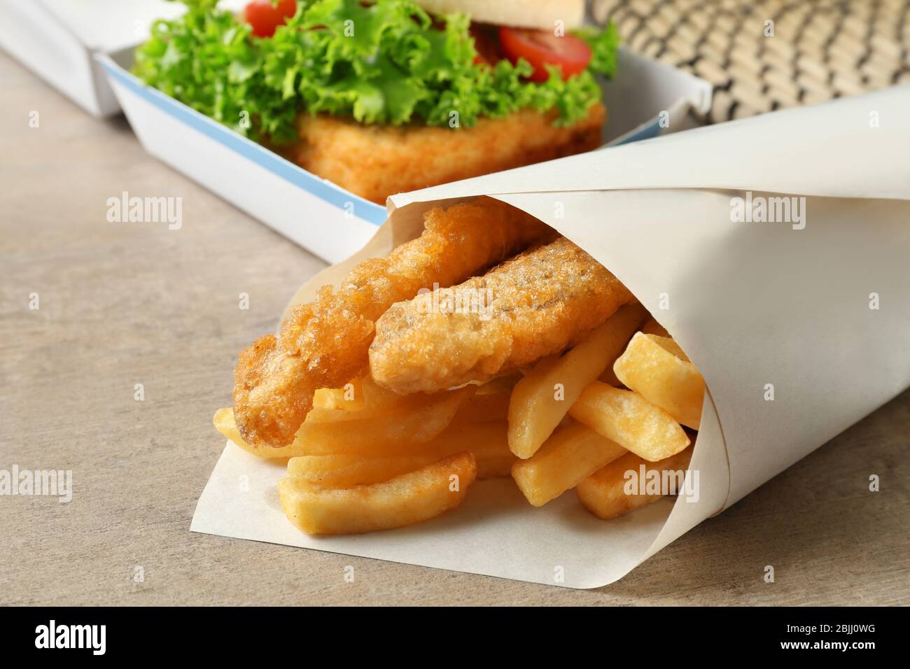 Paper cone with tasty fried fish and chips on table Stock Photo - Alamy