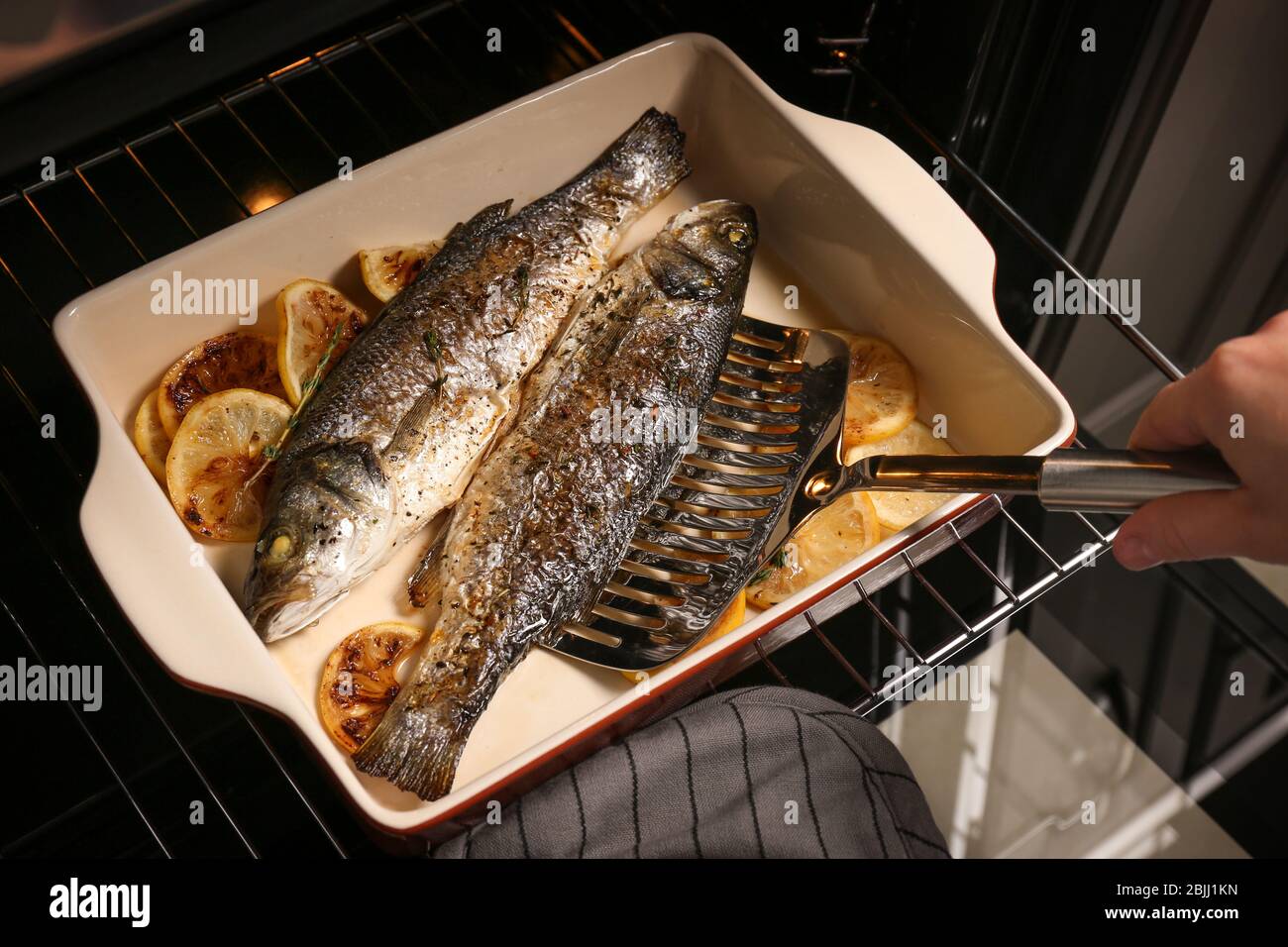Woman cooking fish in oven Stock Photo - Alamy