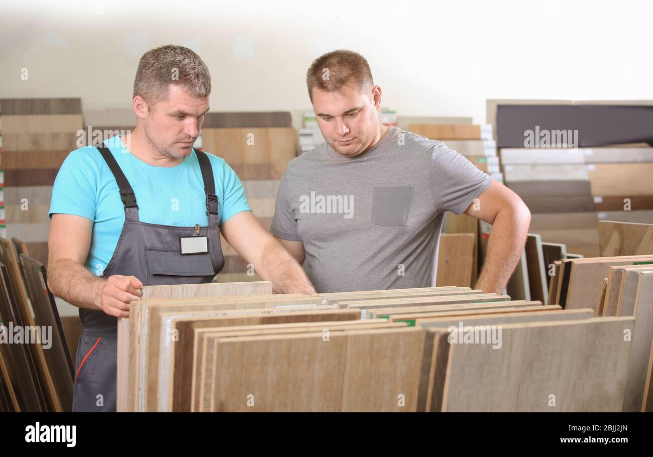Carpenter helping his customer to choose materials in hardware store ...