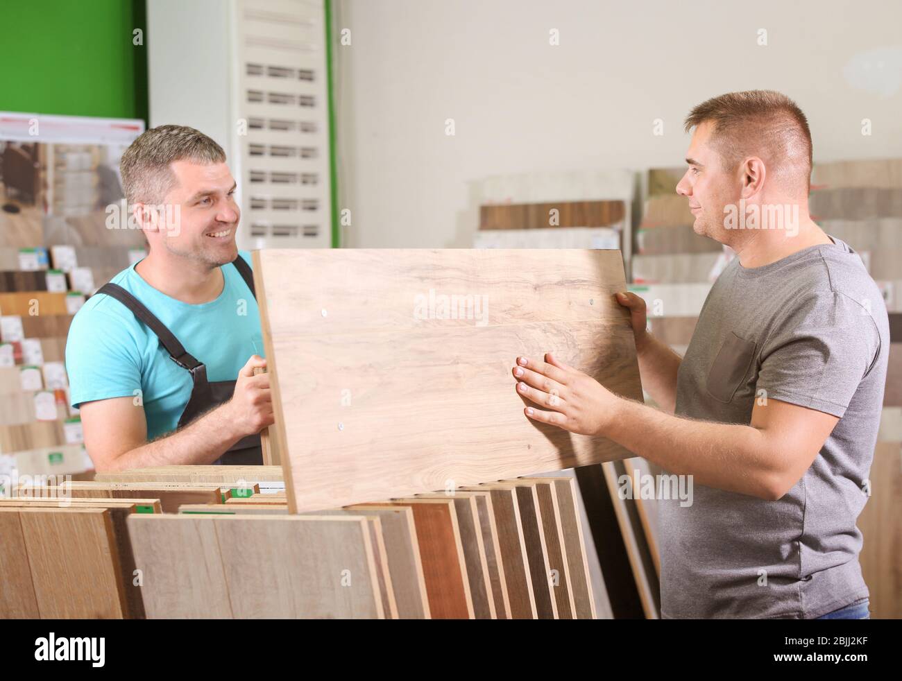 Carpenter helping his customer to choose materials in hardware store ...
