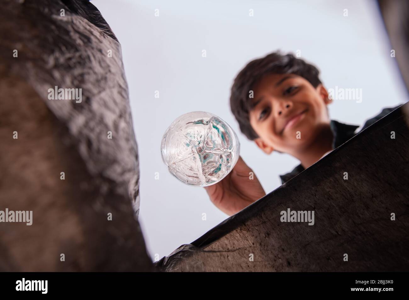 Young boy throwing plastic bottle in a garbage bag. (Children Stock ...