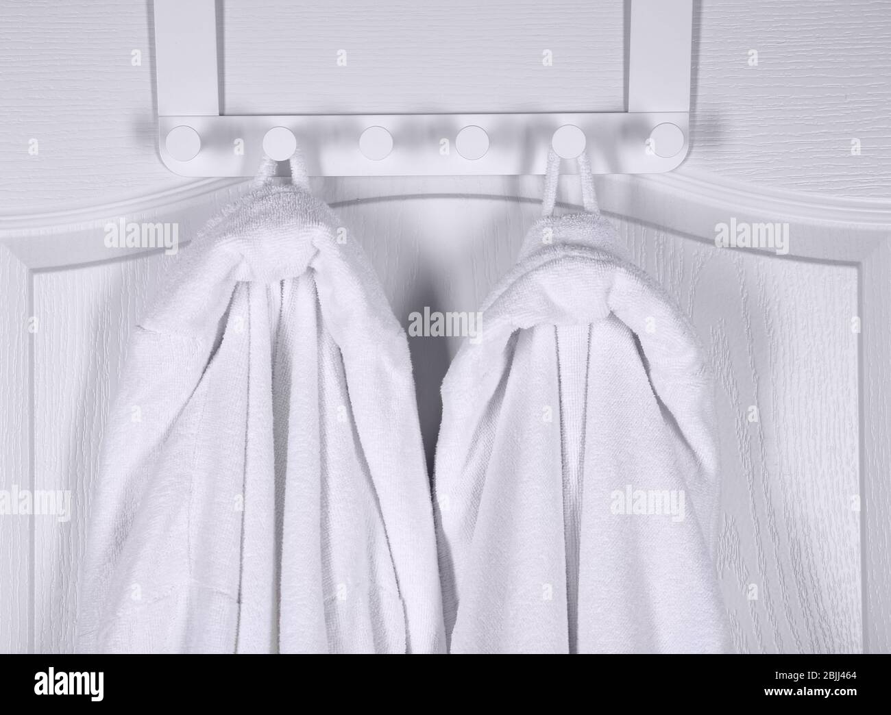 Bathrobes hanging on white door Stock Photo - Alamy