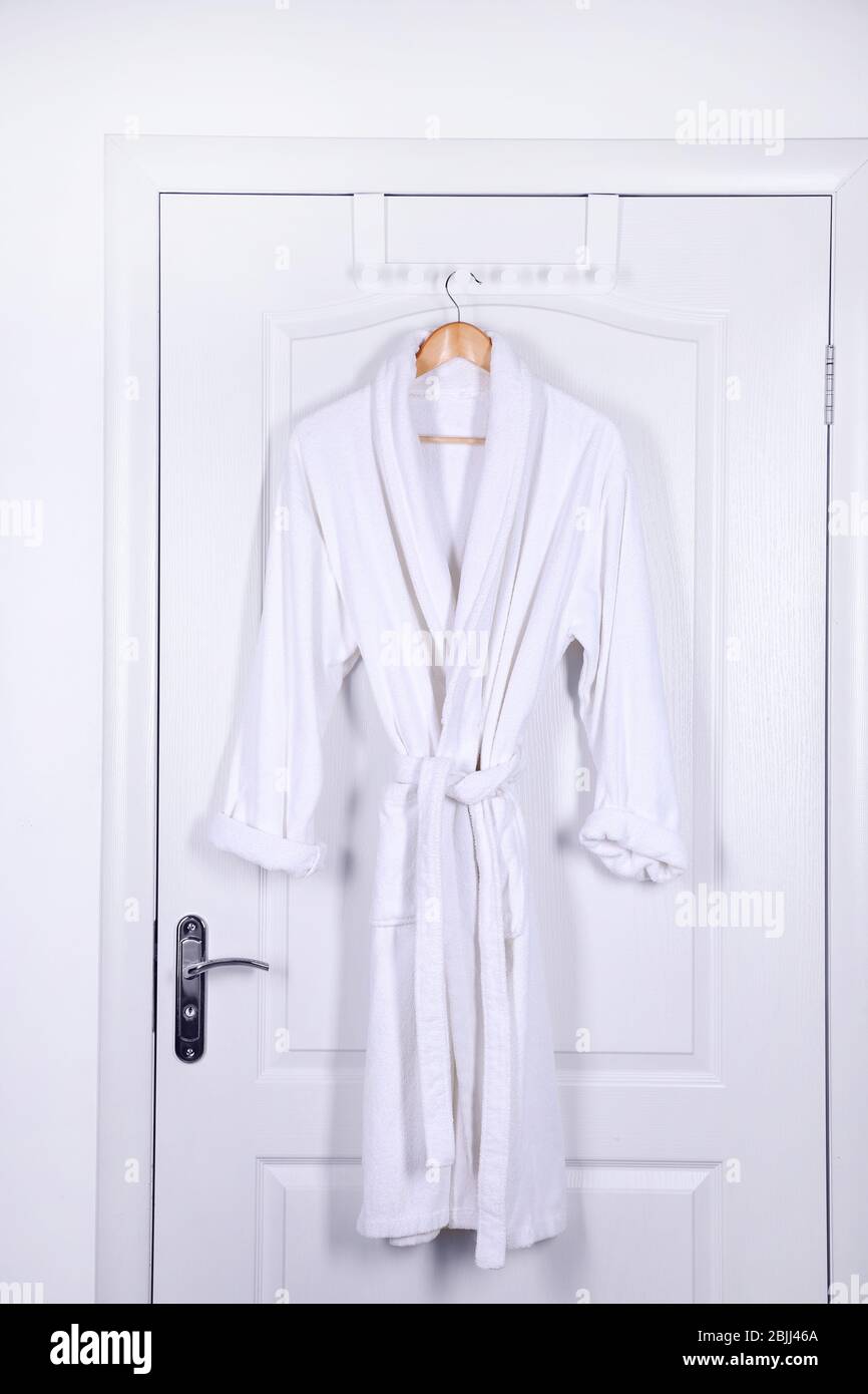 Bathrobe hanging on white door Stock Photo - Alamy
