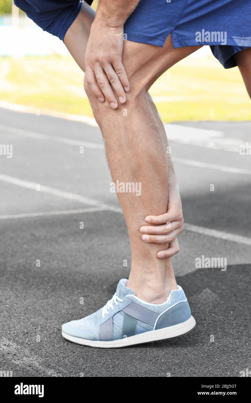 Young man suffering from pain in leg, outdoors Stock Photo - Alamy