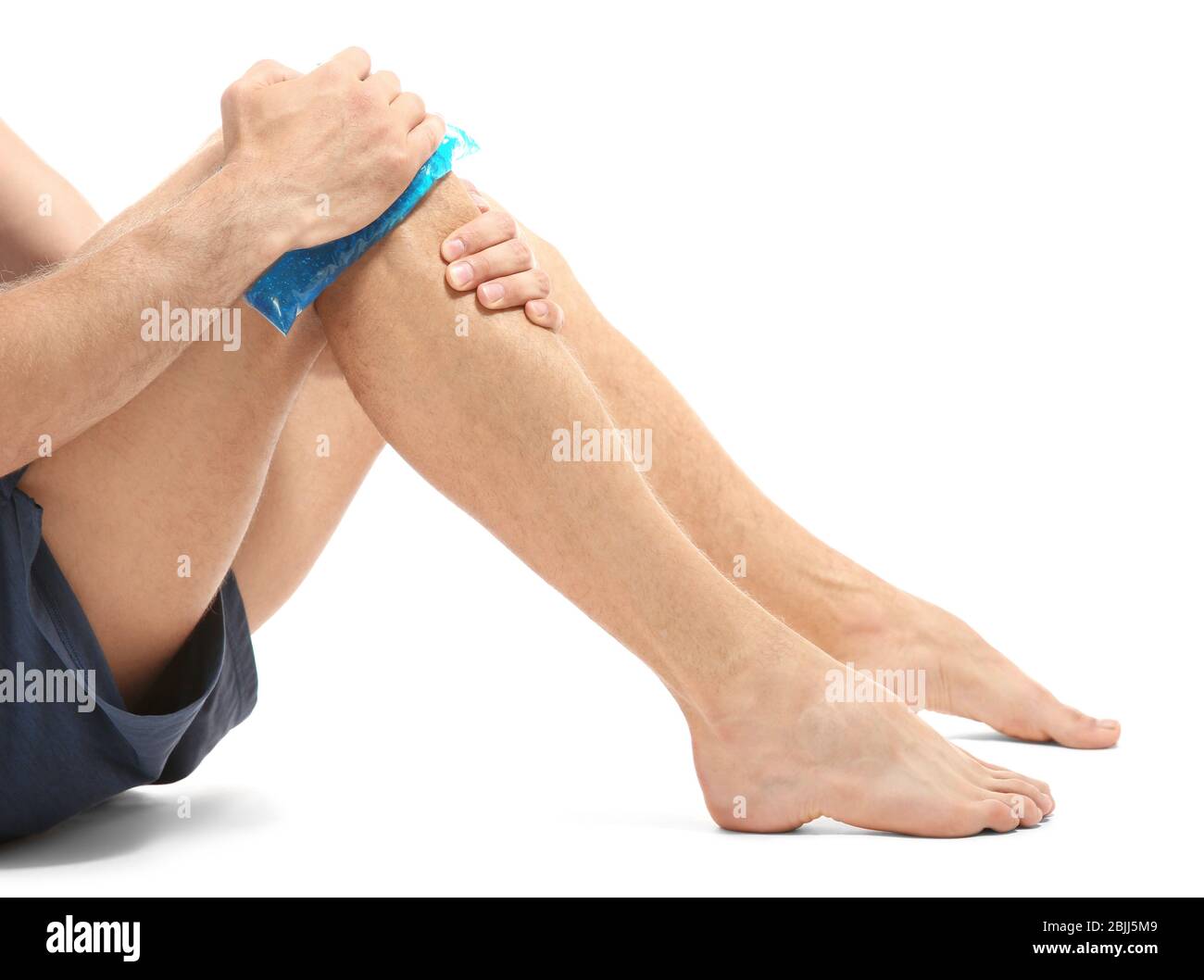 Young man applying cold compress to leg on white background Stock Photo ...