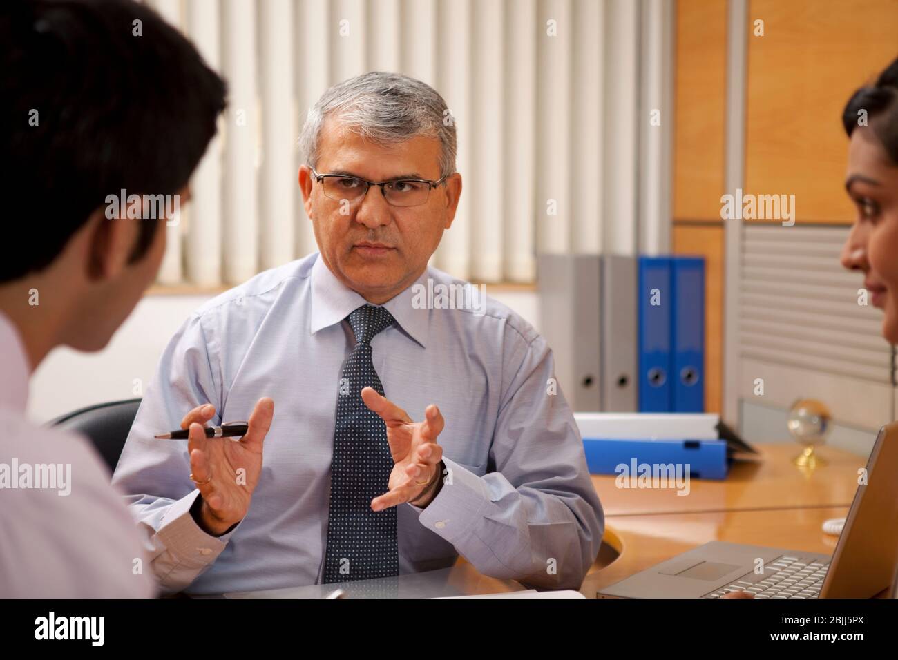 Manager wearing formals explaining to his employees Stock Photo - Alamy