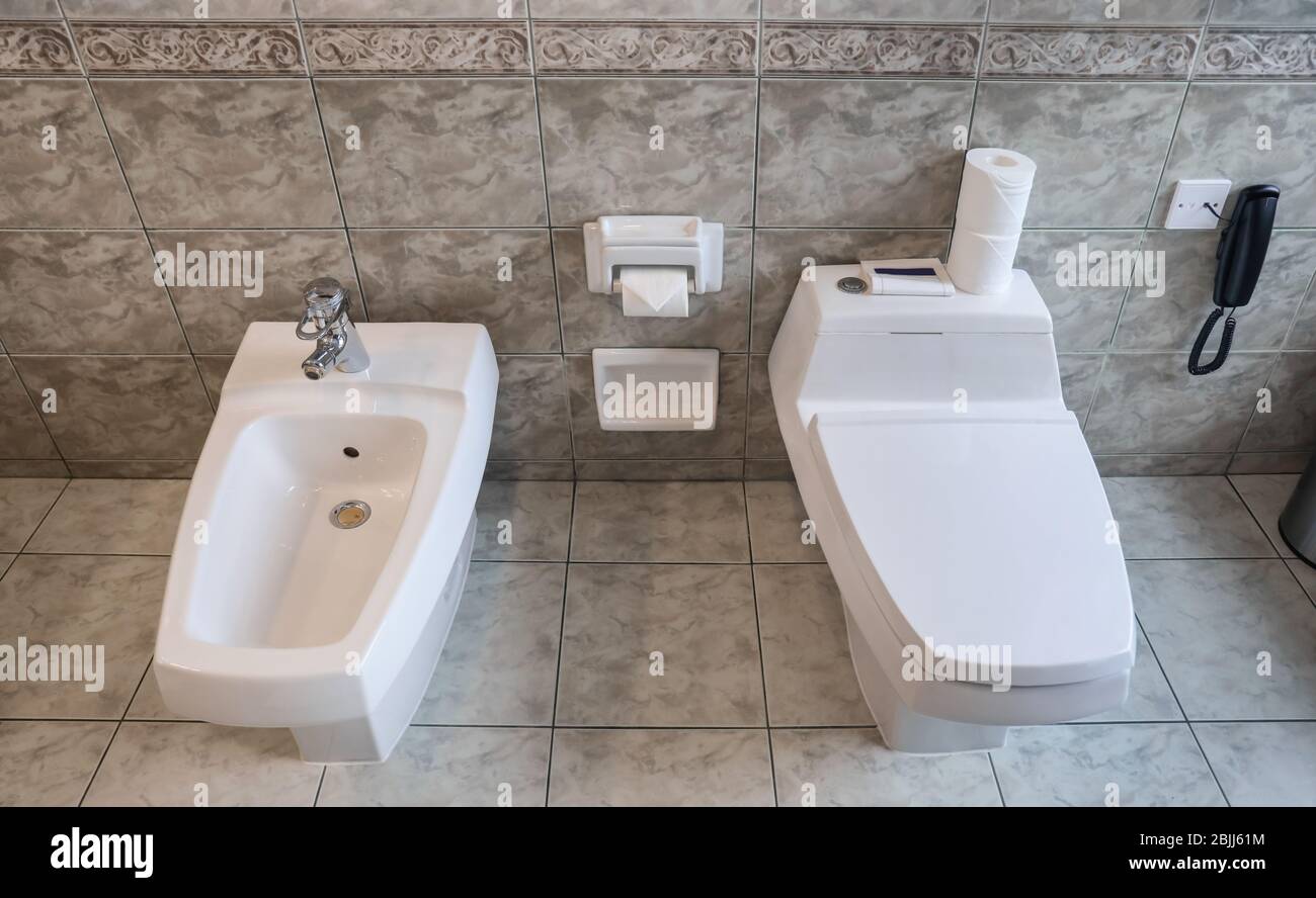 Toilet bowl and bidet in modern hotel bathroom Stock Photo - Alamy