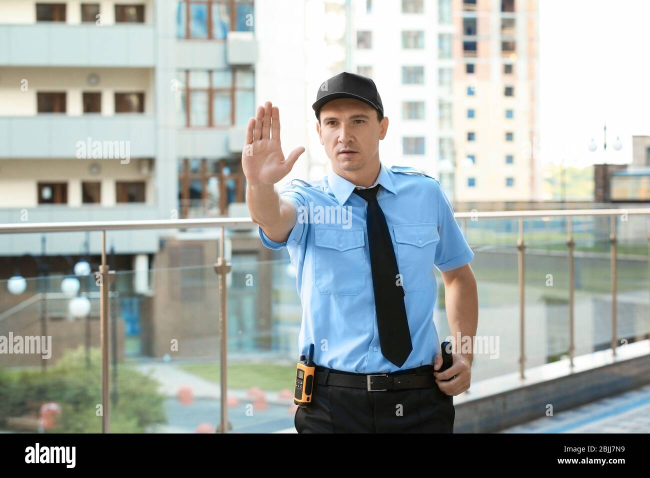 Male security guard showing stop gesture, outdoors Stock Photo - Alamy