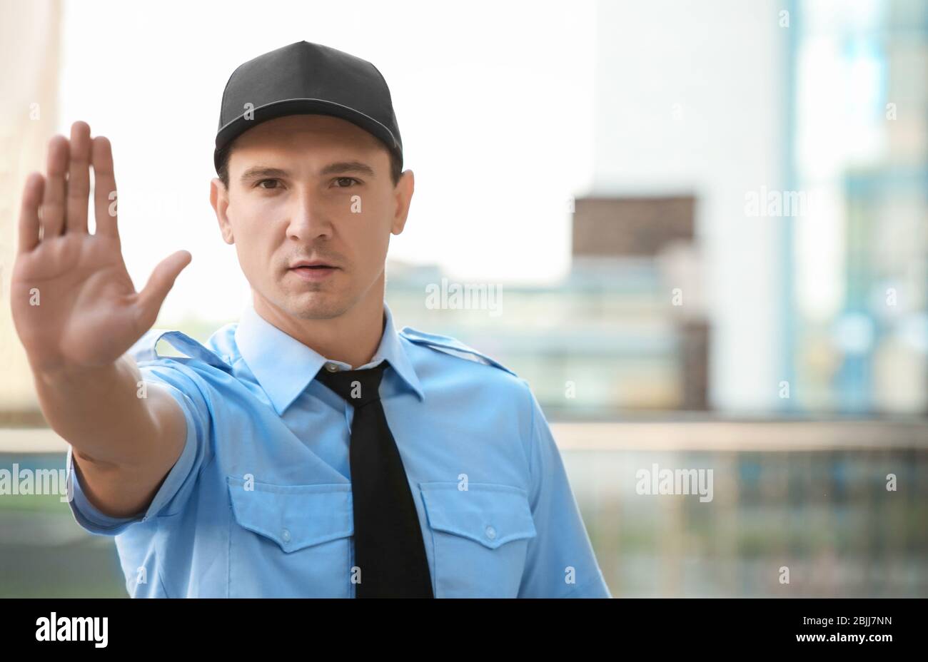 Male security guard showing stop gesture, outdoors Stock Photo - Alamy