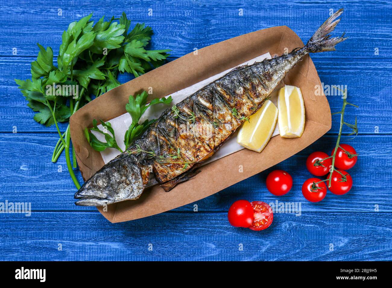 Grilled tasty fish in paper box with vegetables Stock Photo - Alamy