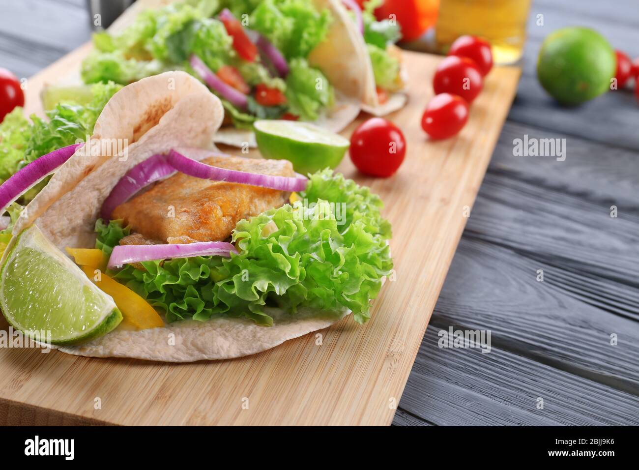 Wooden board with delicious tacos on kitchen table Stock Photo - Alamy