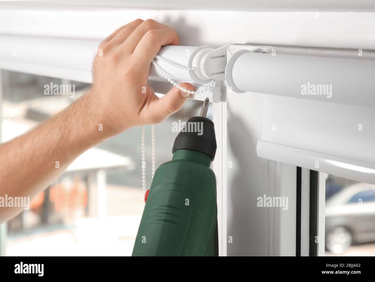 Young man installing window screens indoors Stock Photo - Alamy