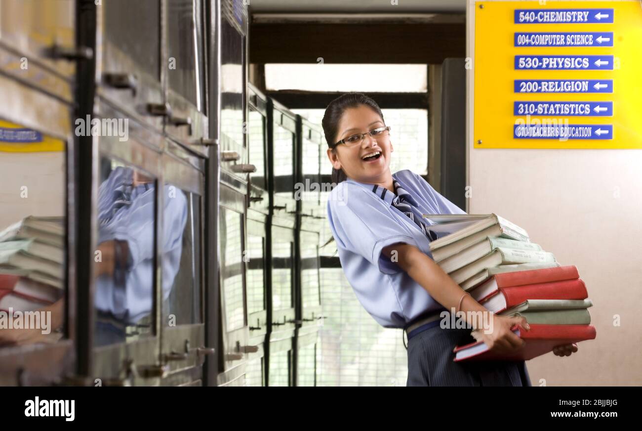Girl carrying a stack of books from a library Stock Photo - Alamy