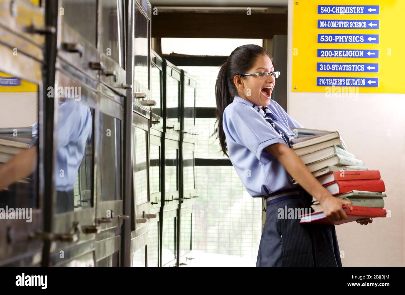 Girl carrying a stack of books from a library Stock Photo - Alamy