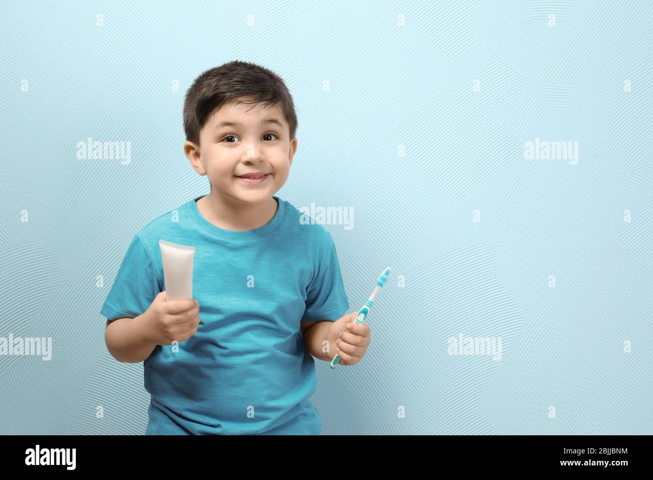 Cute boy with toothbrush and paste on color background. Teeth cleaning ...