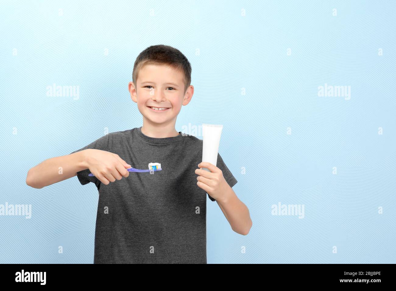 Cute boy with toothbrush and paste on color background. Teeth cleaning ...