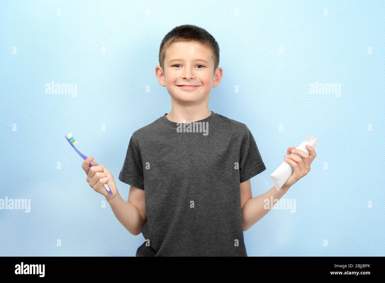 Cute boy with toothbrush and paste on color background. Teeth cleaning ...
