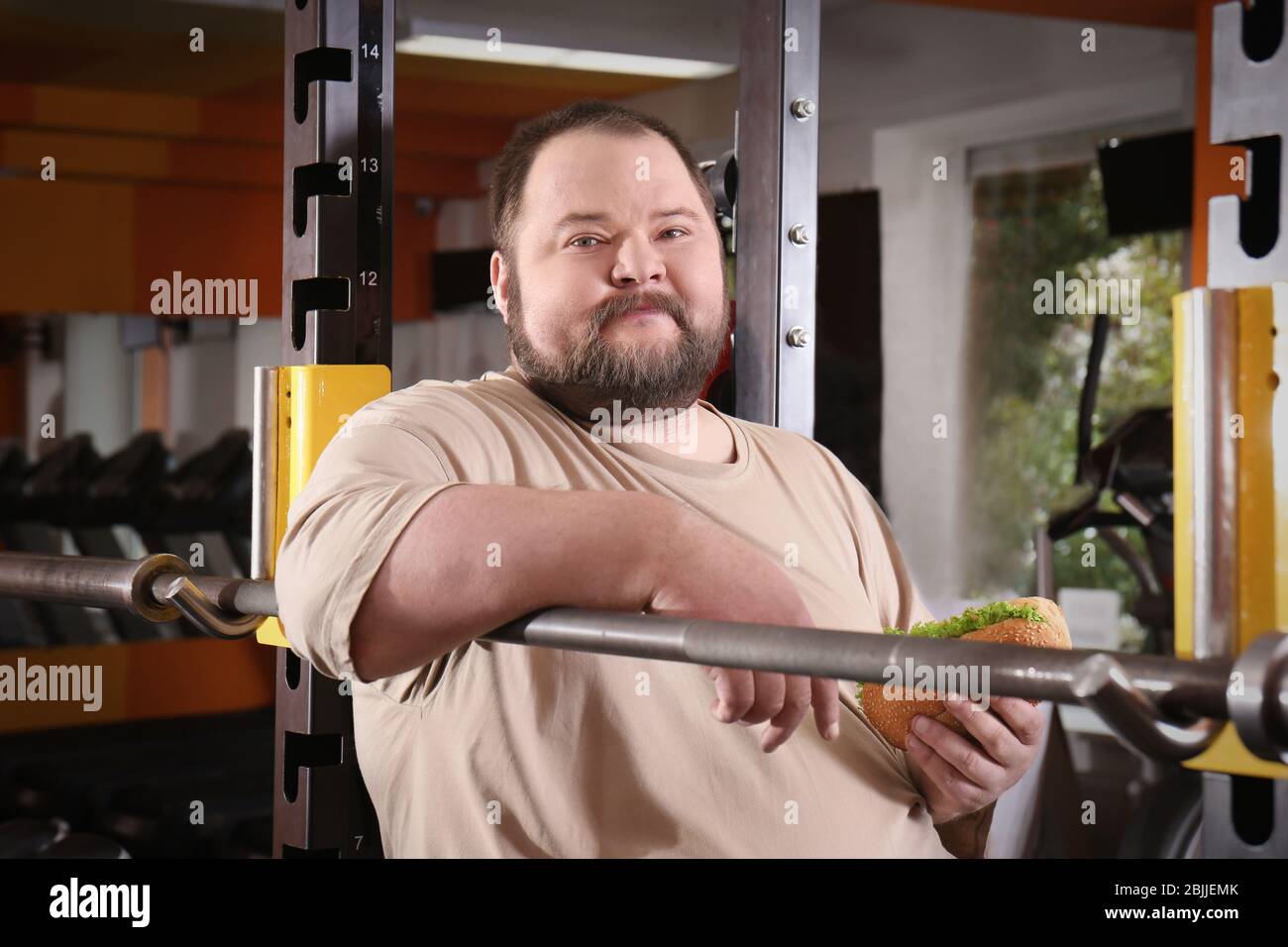 Overweight man eating sandwich in gym Stock Photo - Alamy