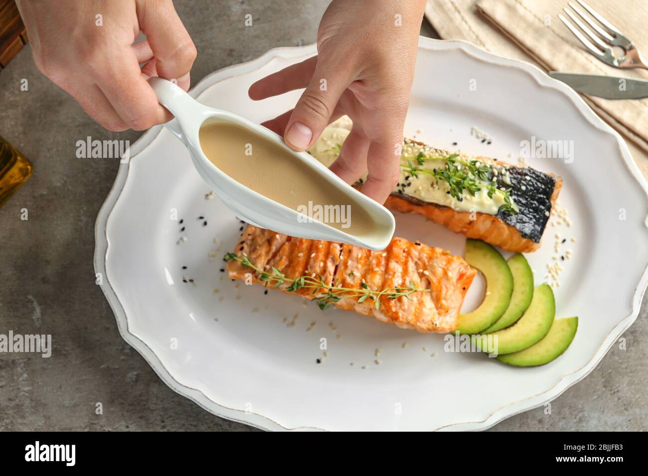 Woman pouring fish sauce onto plate with delicious salmon Stock Photo ...