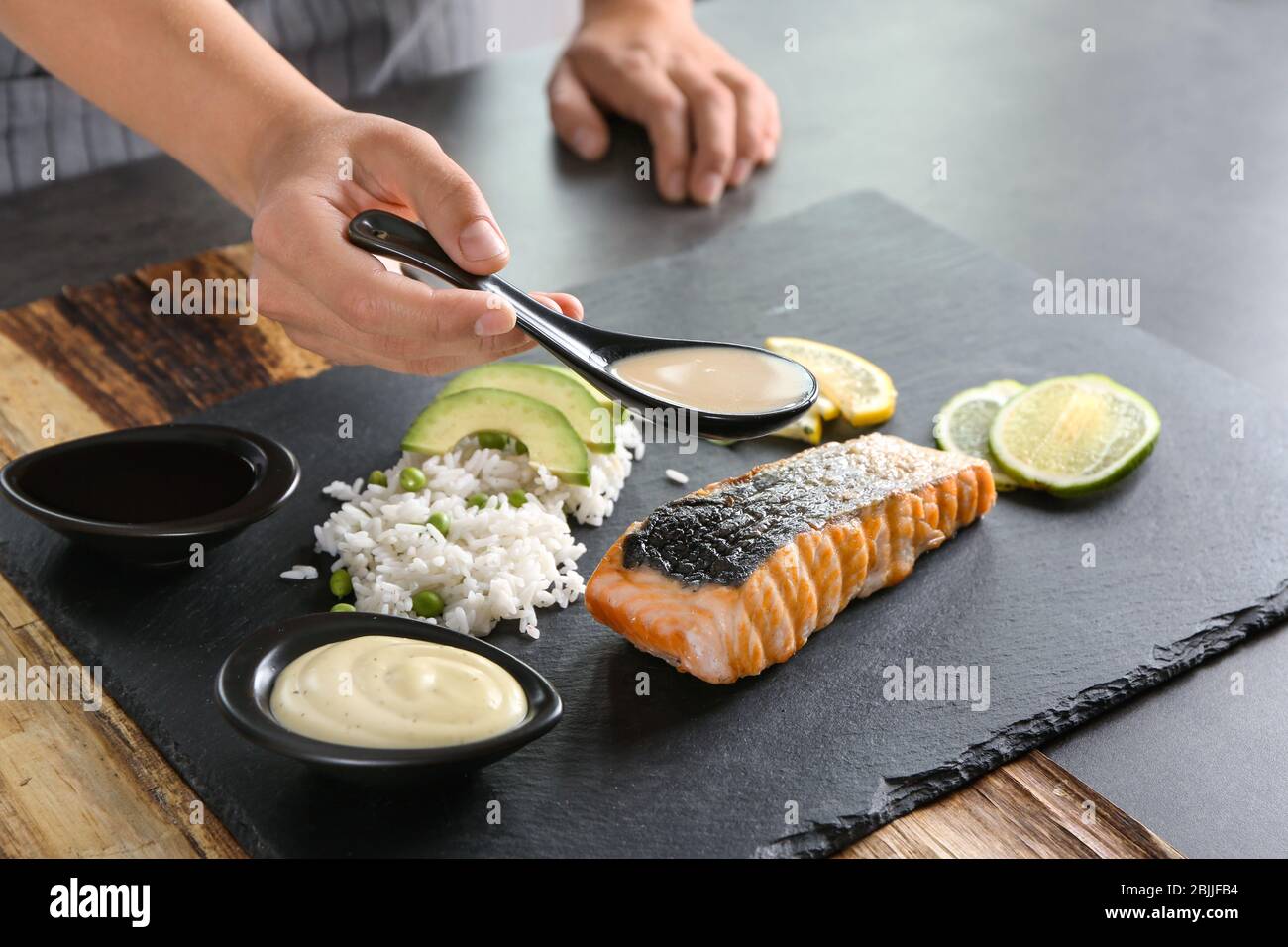 Woman pouring fish sauce on delicious salmon Stock Photo - Alamy