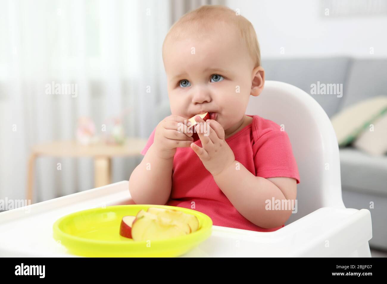 Little baby eating apple indoors Stock Photo - Alamy