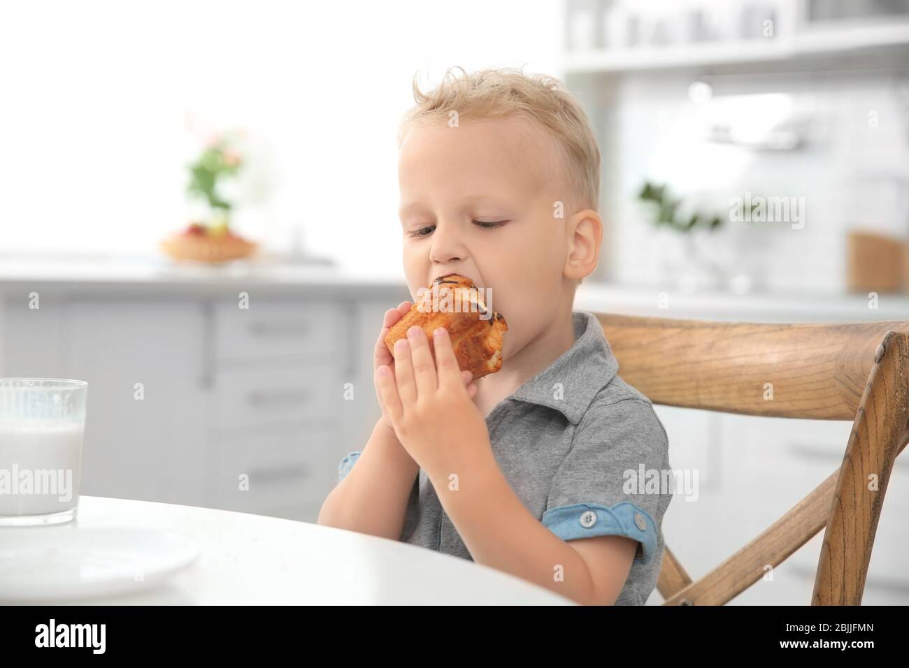 Cute little boy eating big muffin in kitchen Stock Photo - Alamy