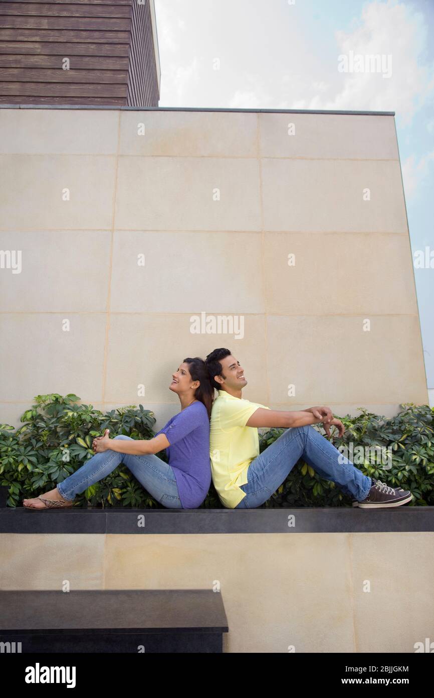 Couple sitting back to back Stock Photo - Alamy