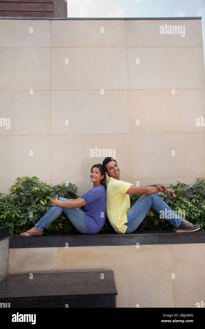 Portrait of a couple sitting back to back Stock Photo - Alamy