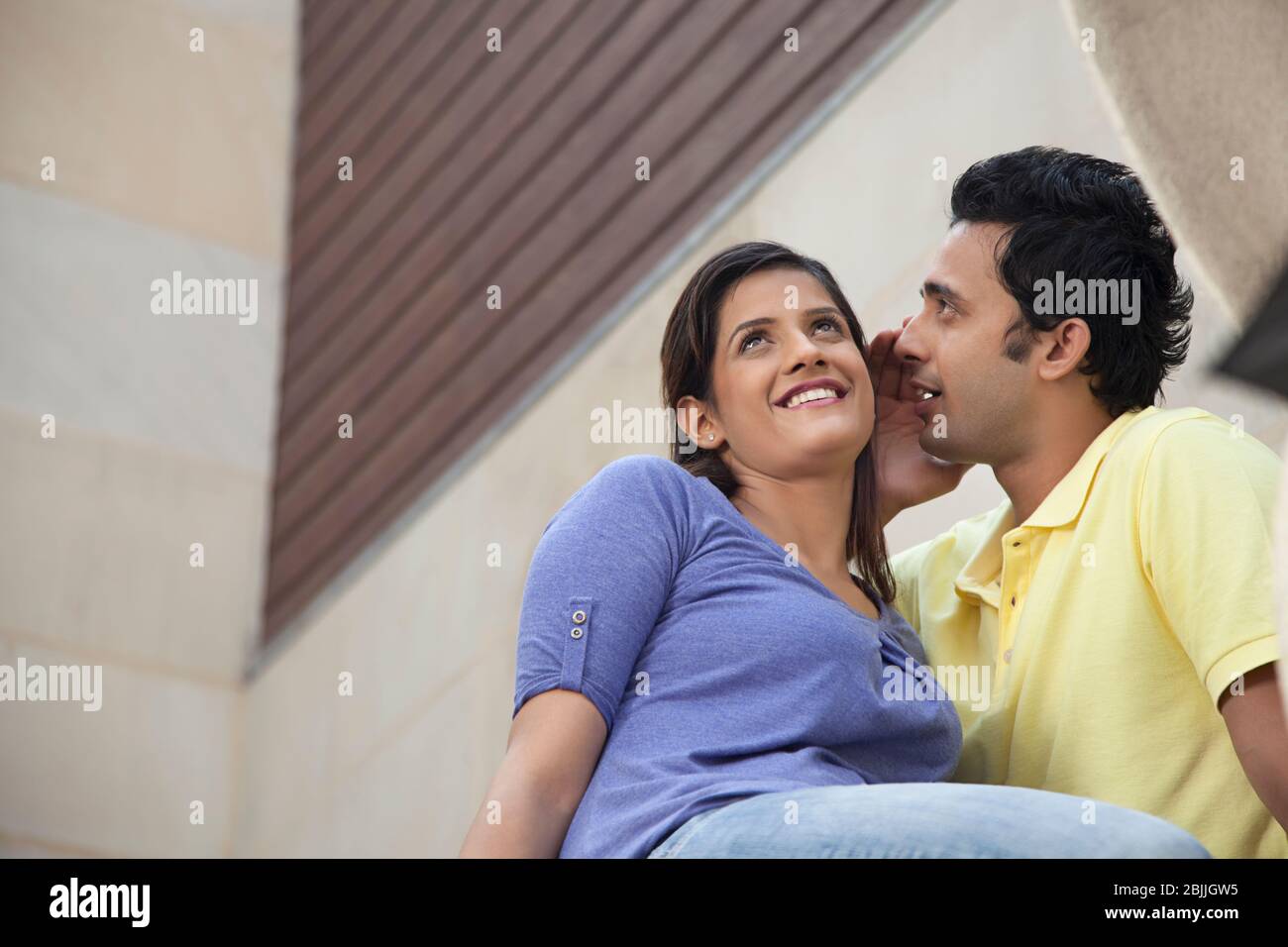 Man whispering in a womans ear Stock Photo - Alamy