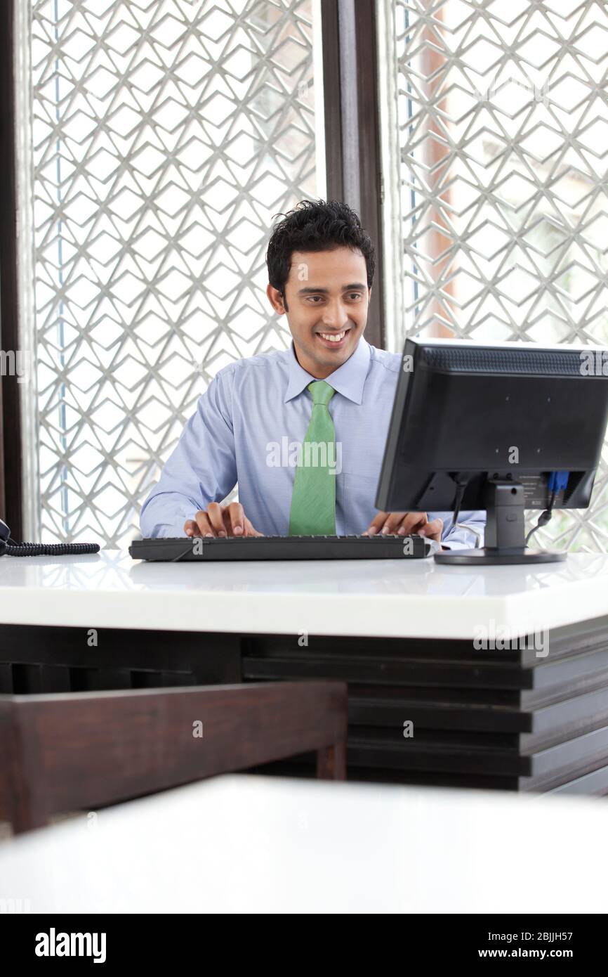 Indian man sitting at reception desk hi-res stock photography and ...