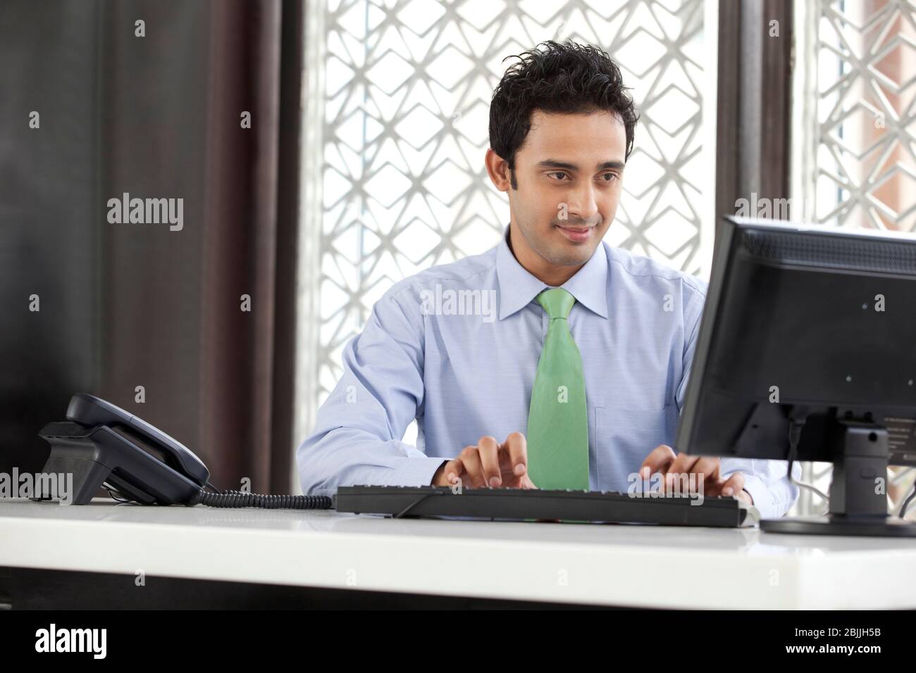 Indian man sitting at reception desk hi-res stock photography and ...
