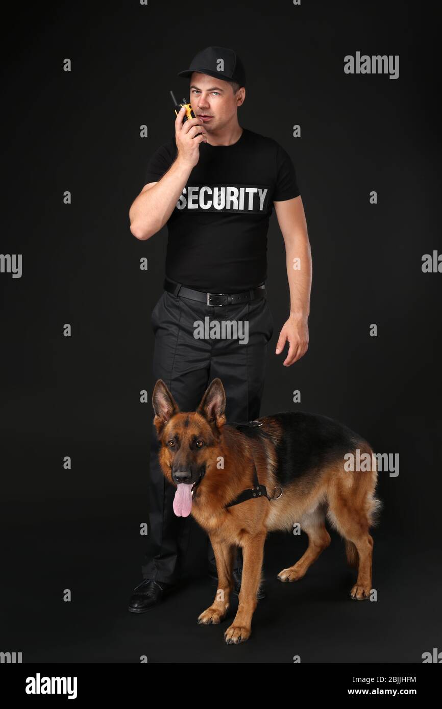 Security guard with dog on black background Stock Photo - Alamy