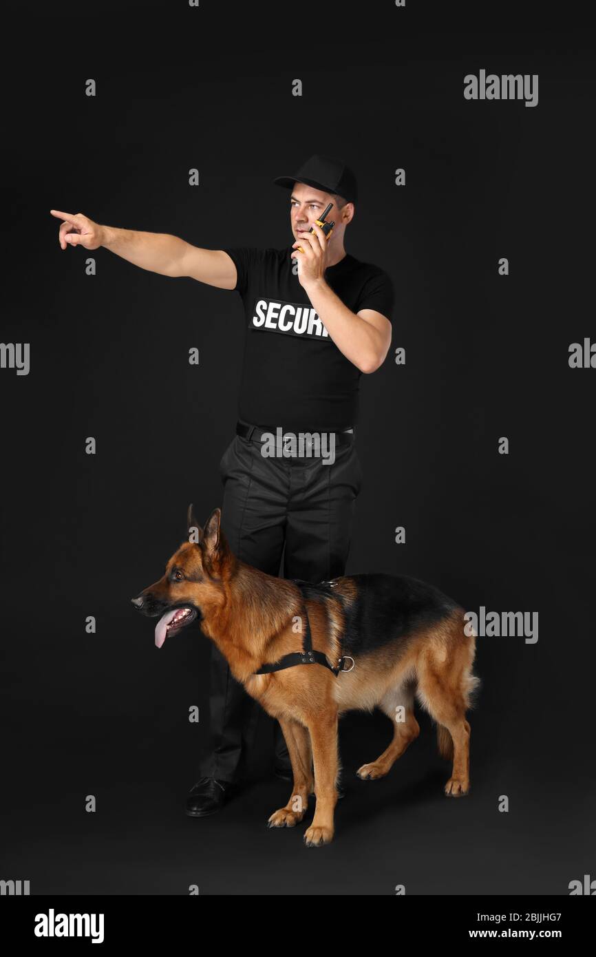 Security guard with dog on black background Stock Photo - Alamy