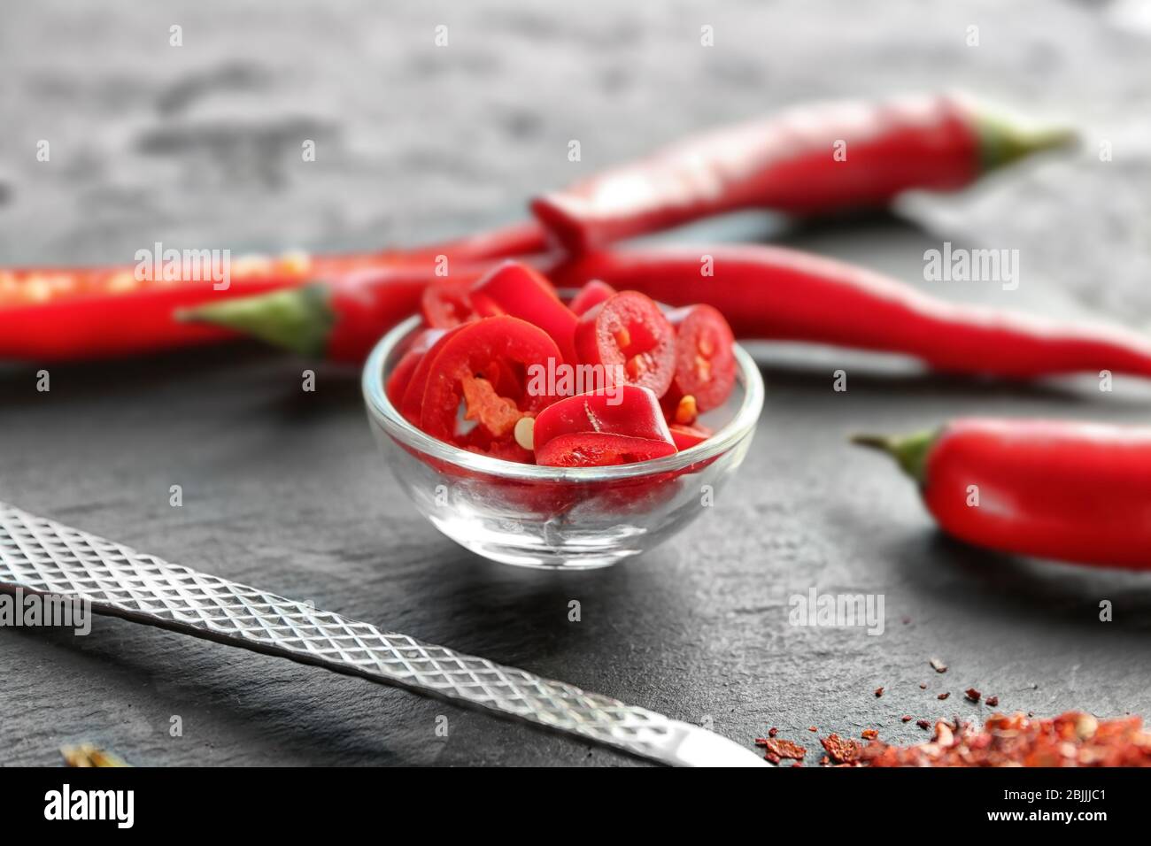 Red chili pepper slices in glass bowl on dark table Stock Photo - Alamy