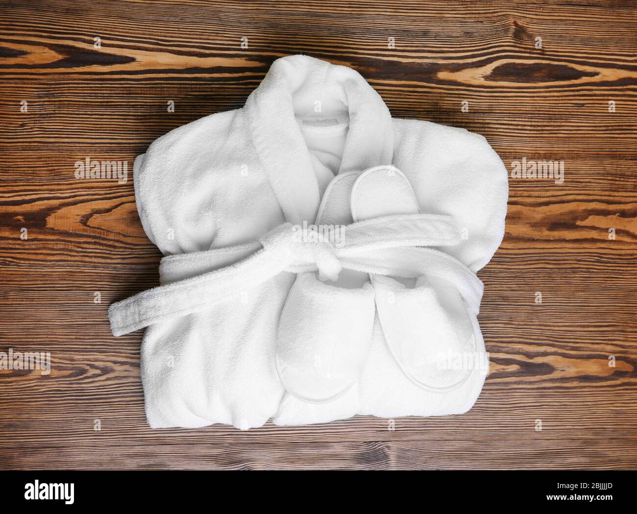 Folded bathrobe and bathing slippers on wooden background Stock Photo ...
