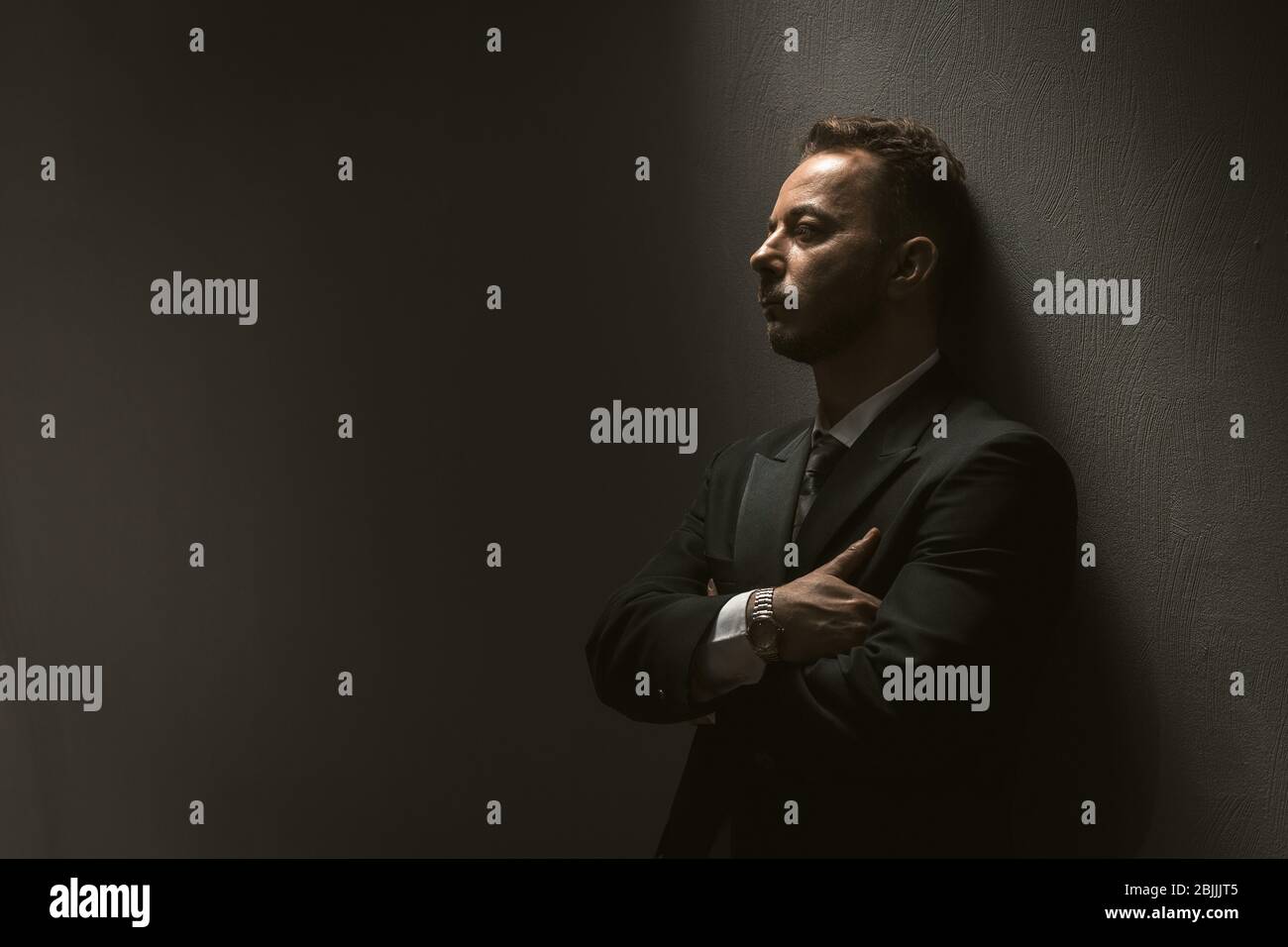 Sad man in black suit on black background Stock Photo - Alamy