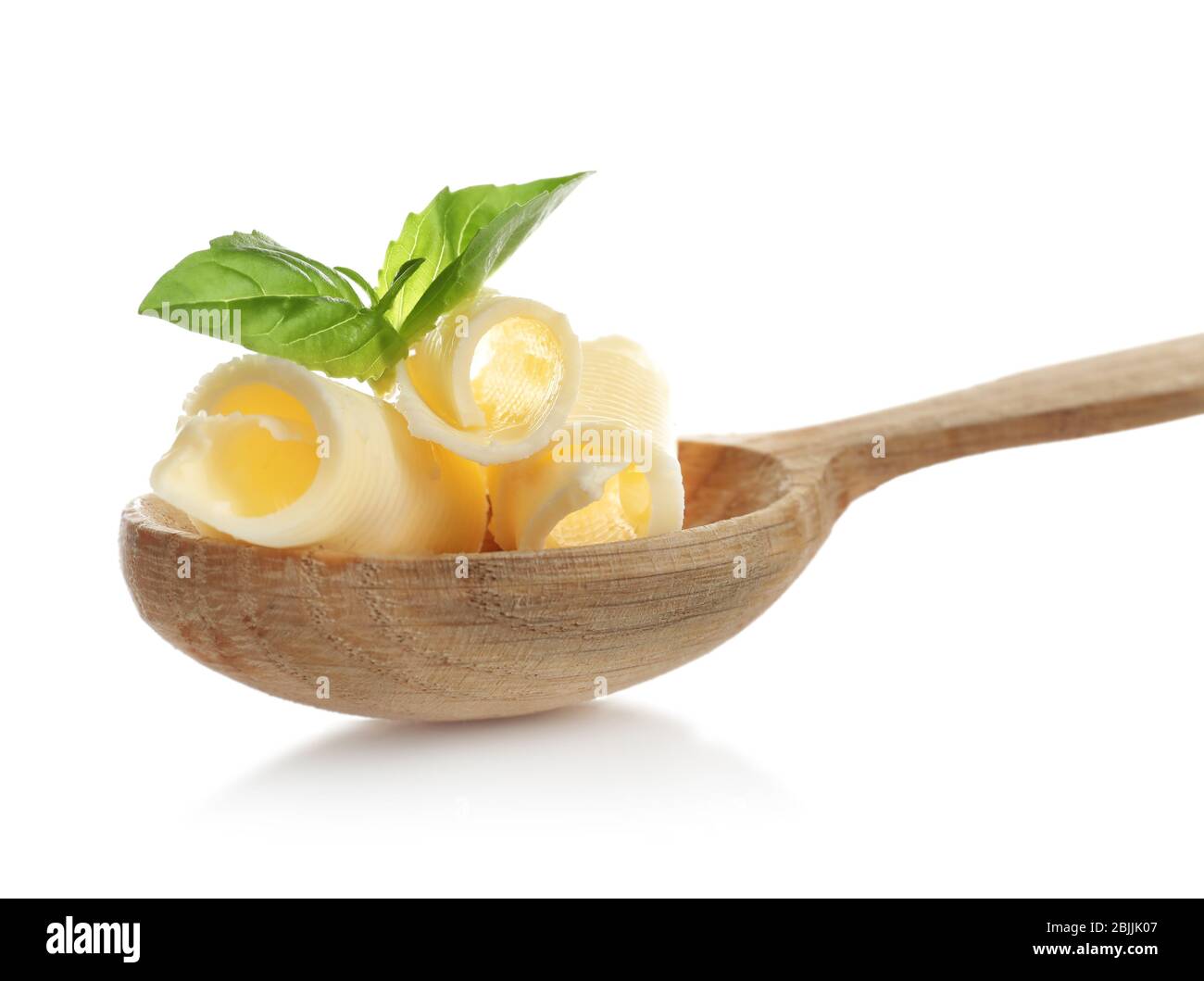 Wooden spoon with delicious butter curls and basil on white background ...