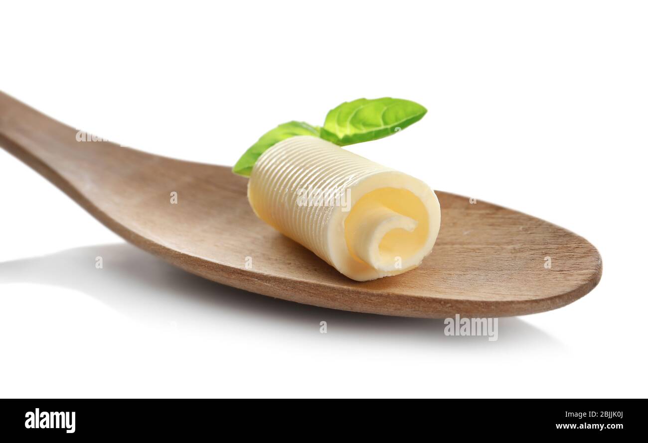 Wooden spoon with delicious butter curl and basil on white background ...