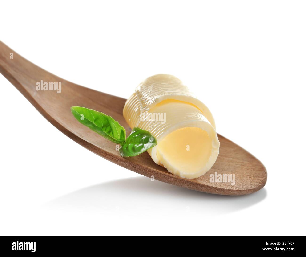 Wooden spoon with delicious butter curl and basil on white background ...