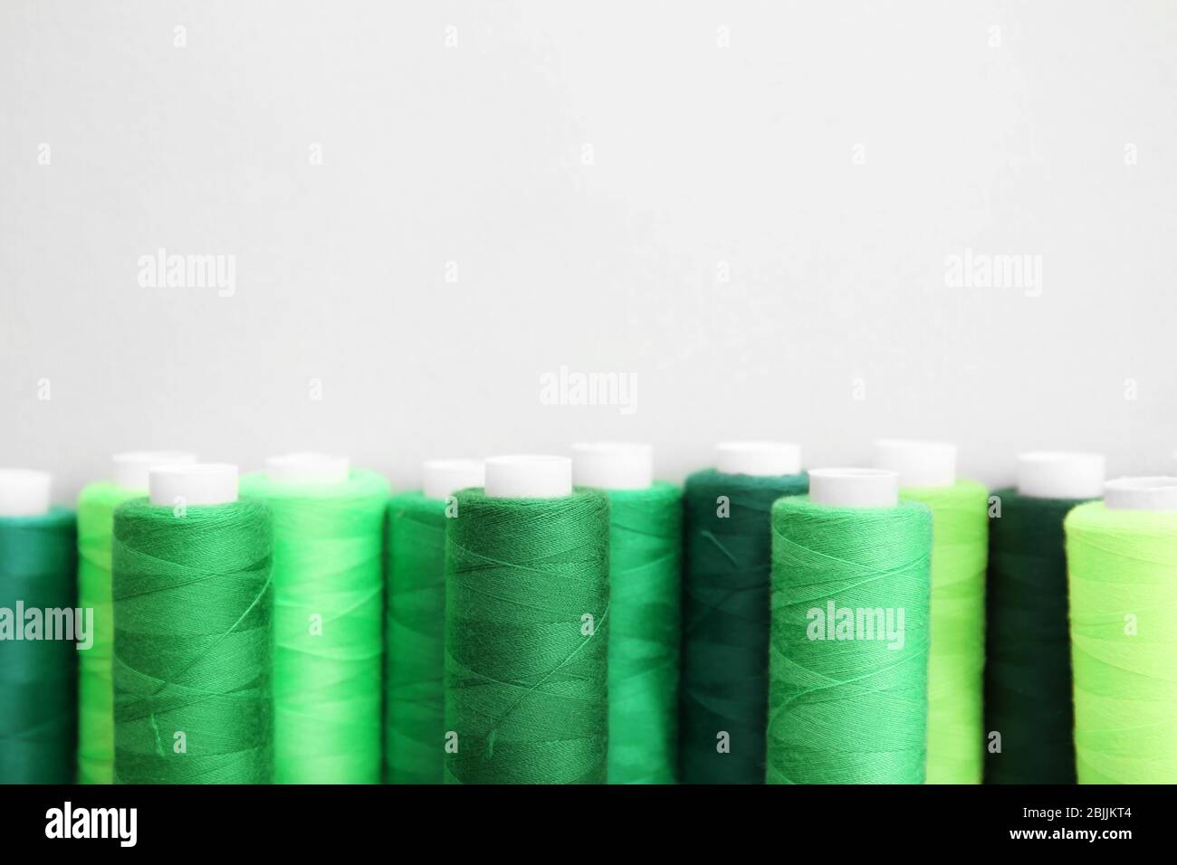 Green sewing threads on white background Stock Photo - Alamy